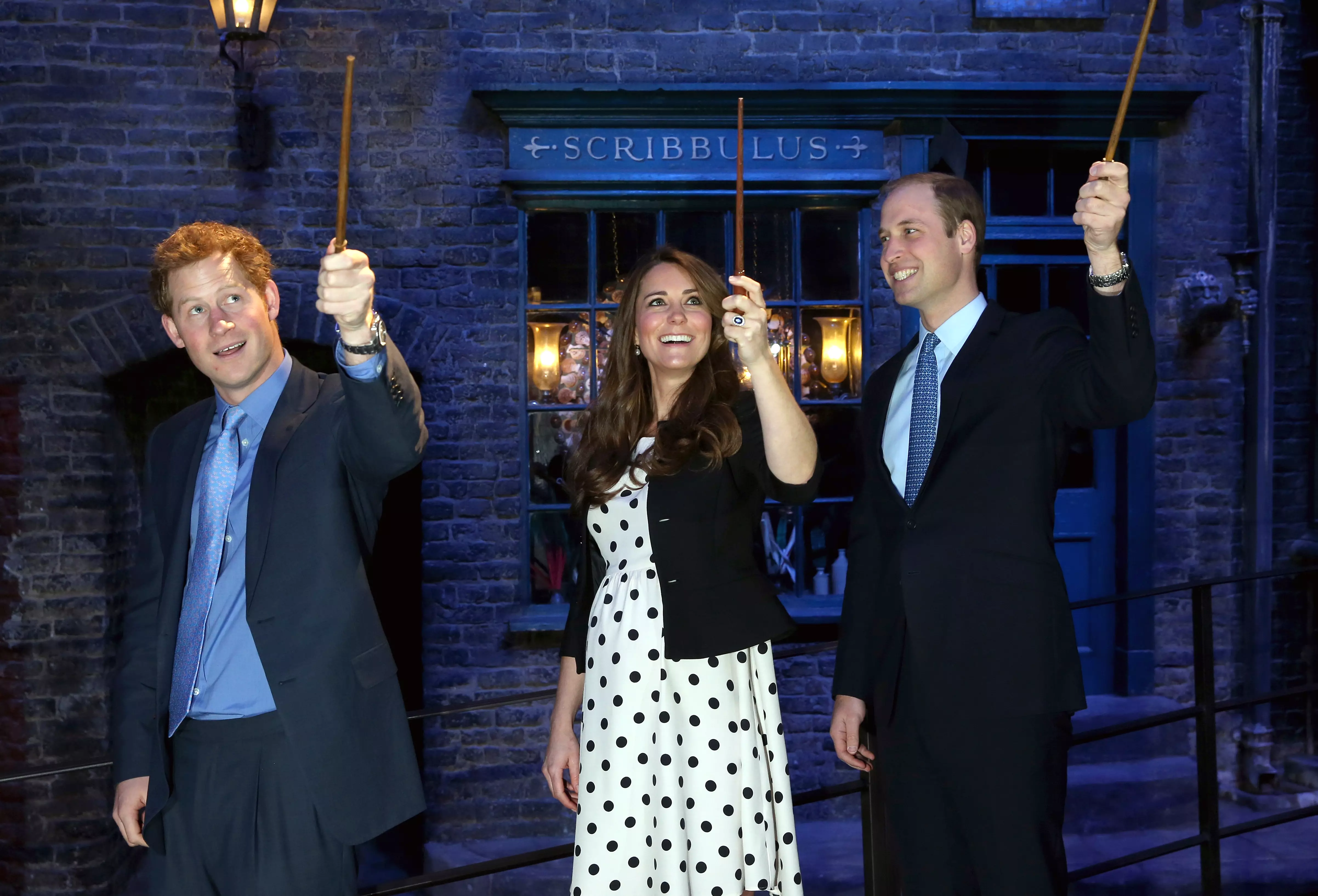 Prins William, Kate Middleton og prins Harry hæver deres tryllestave på sættet, der bruges til at afbilde Diagon Alley i Harry Potter-filmene under indvielsen af Warner Bros Studios